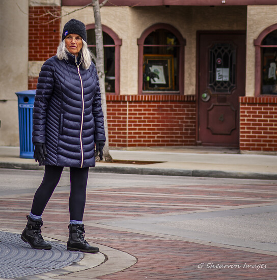 Woman looks at a commotion being caused down the street as she waits on ...